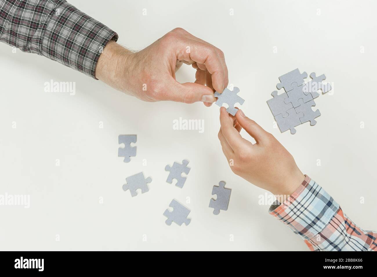 The hands of an adult and a child are holding a puzzle. Generation ...