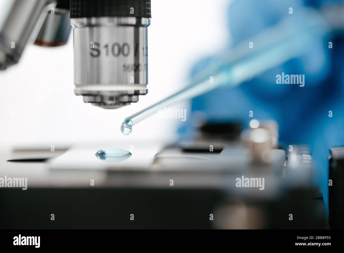 dripping liquid onto slide under microscope to make coronavirus test in ...