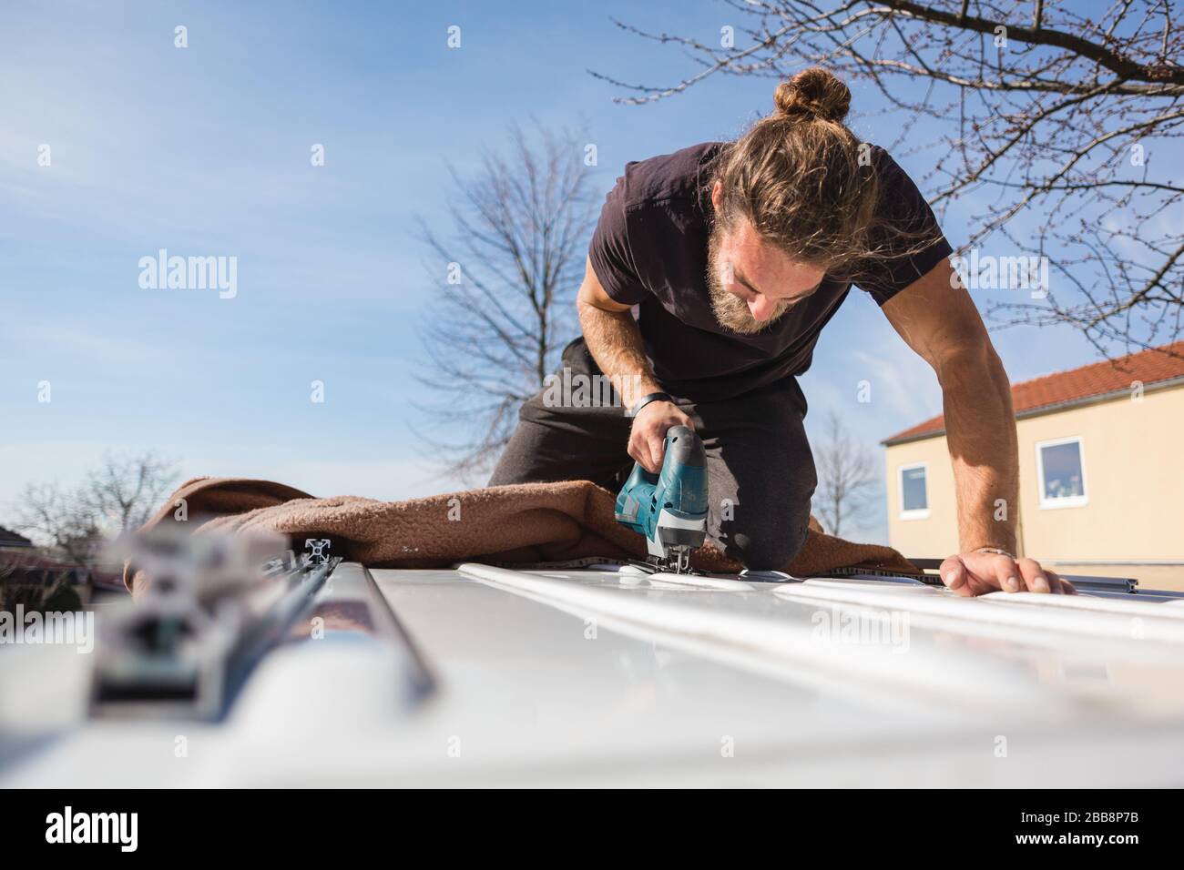 Man using a jigsaw to saw into the roof of a van Stock Photo - Alamy