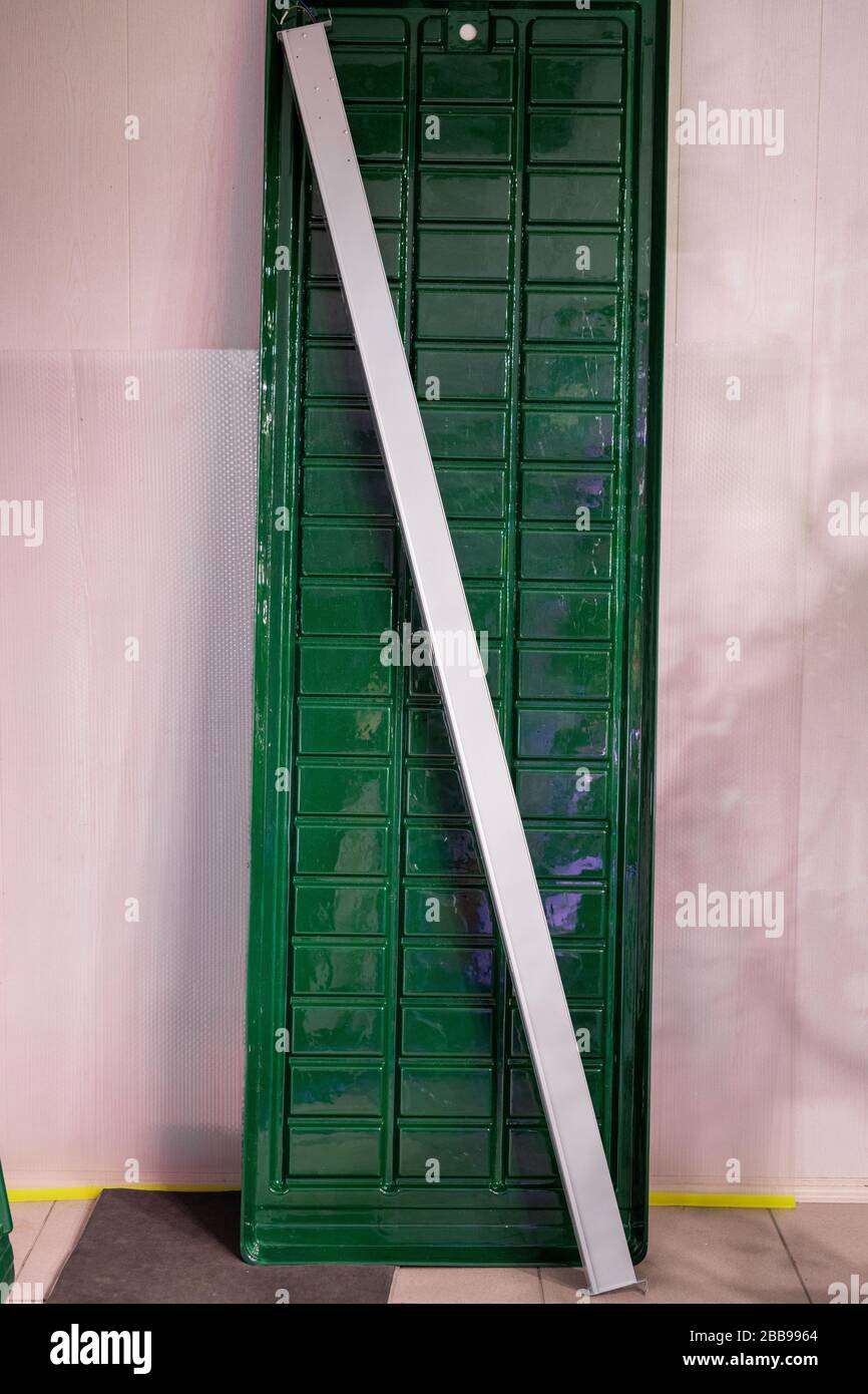 Green long plastic pallet for potted plants leaning with metal plank on ...