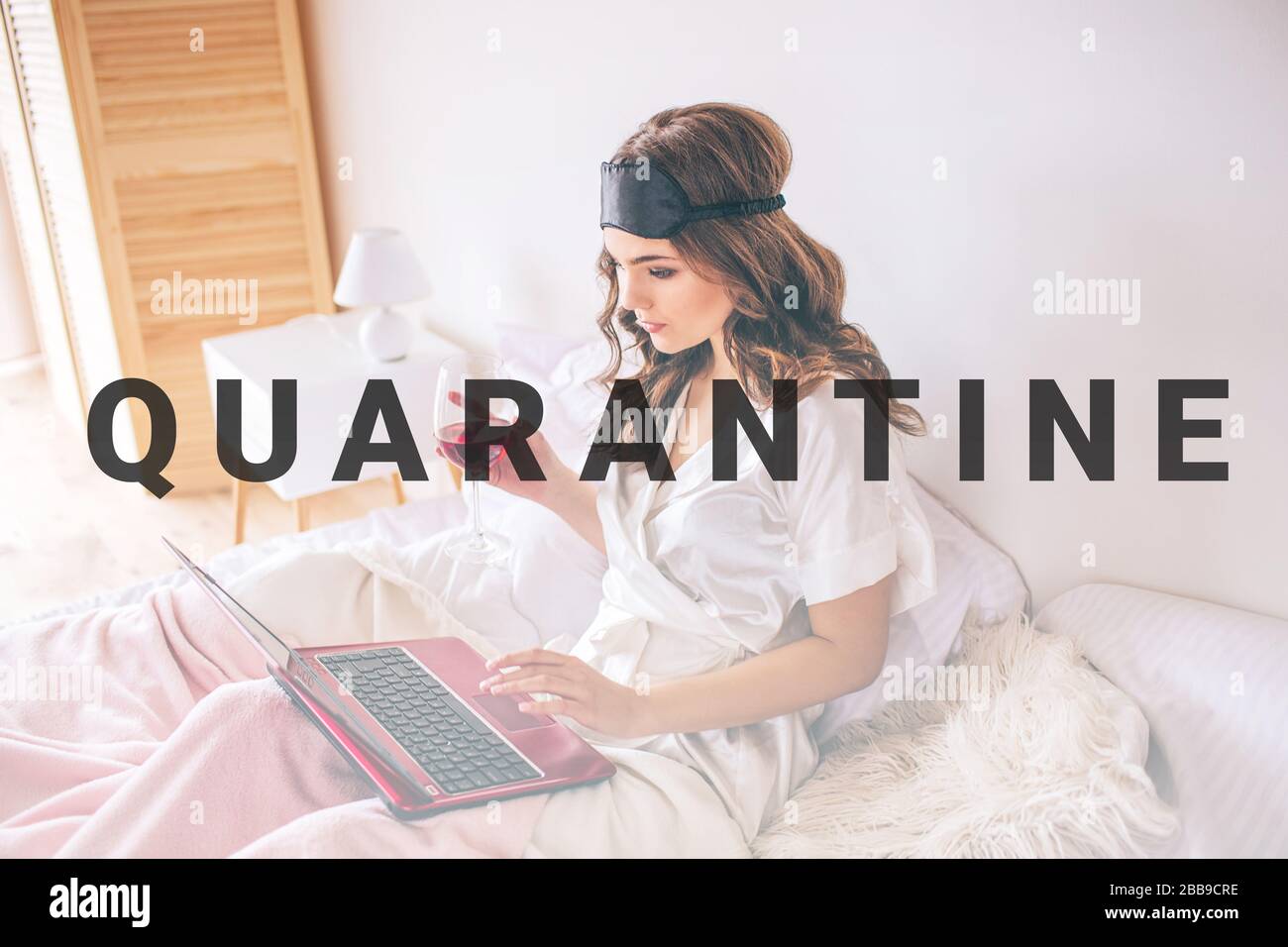 Young woman with dark hair sitting on bed in bedroom and working ...
