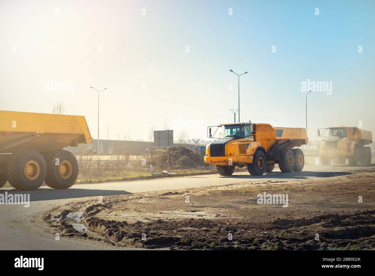 Many big articulated heavy industrial yellow dumper trucks driving on ...