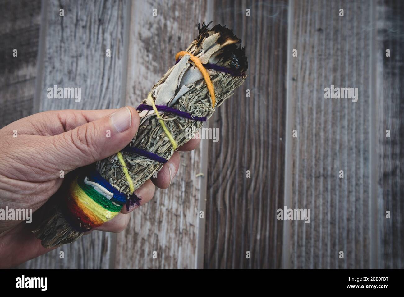 Hand Holding Smoking Sage Bundle on Wood Background Stock Photo - Alamy