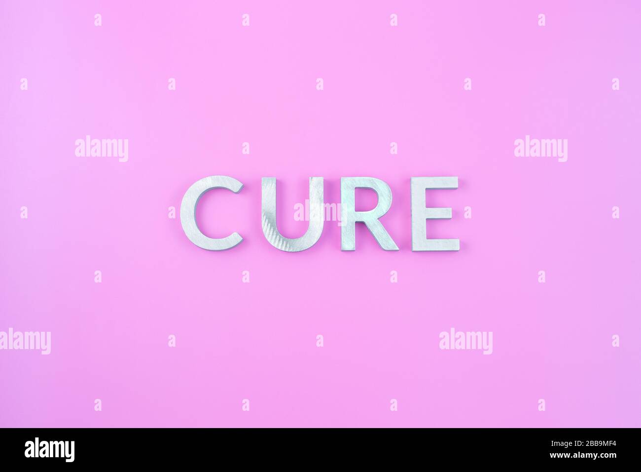 the word cure laid with thick aluminium letters on pink background in ...
