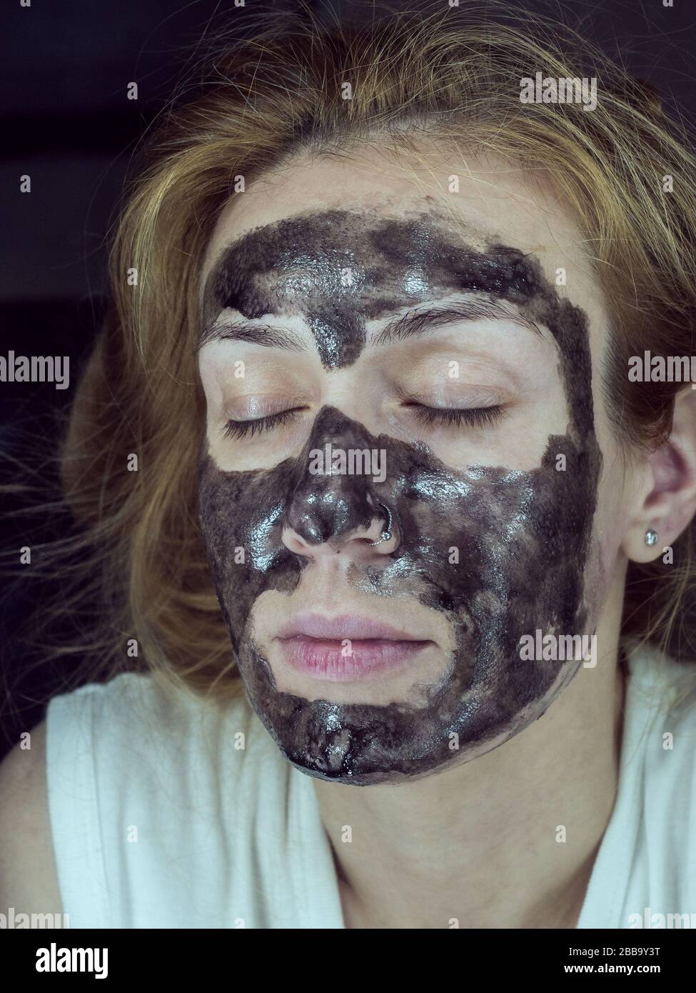 Close-up photo of girl with closed eyes and a black peel off mask on ...