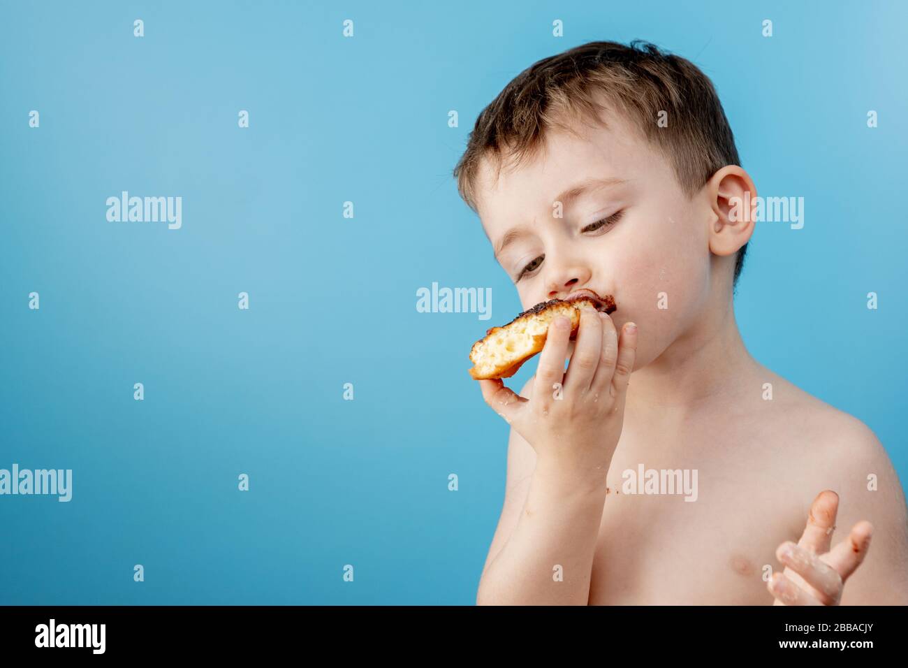 Little boy eating donut chocolate on blue background. Cute happy boy ...