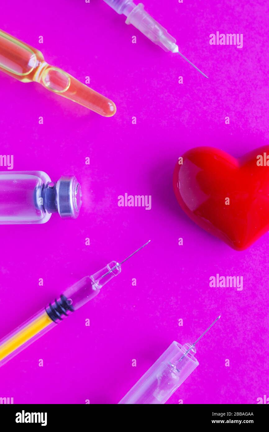 volumetric heart with syringes on a pink background. The concept of ...