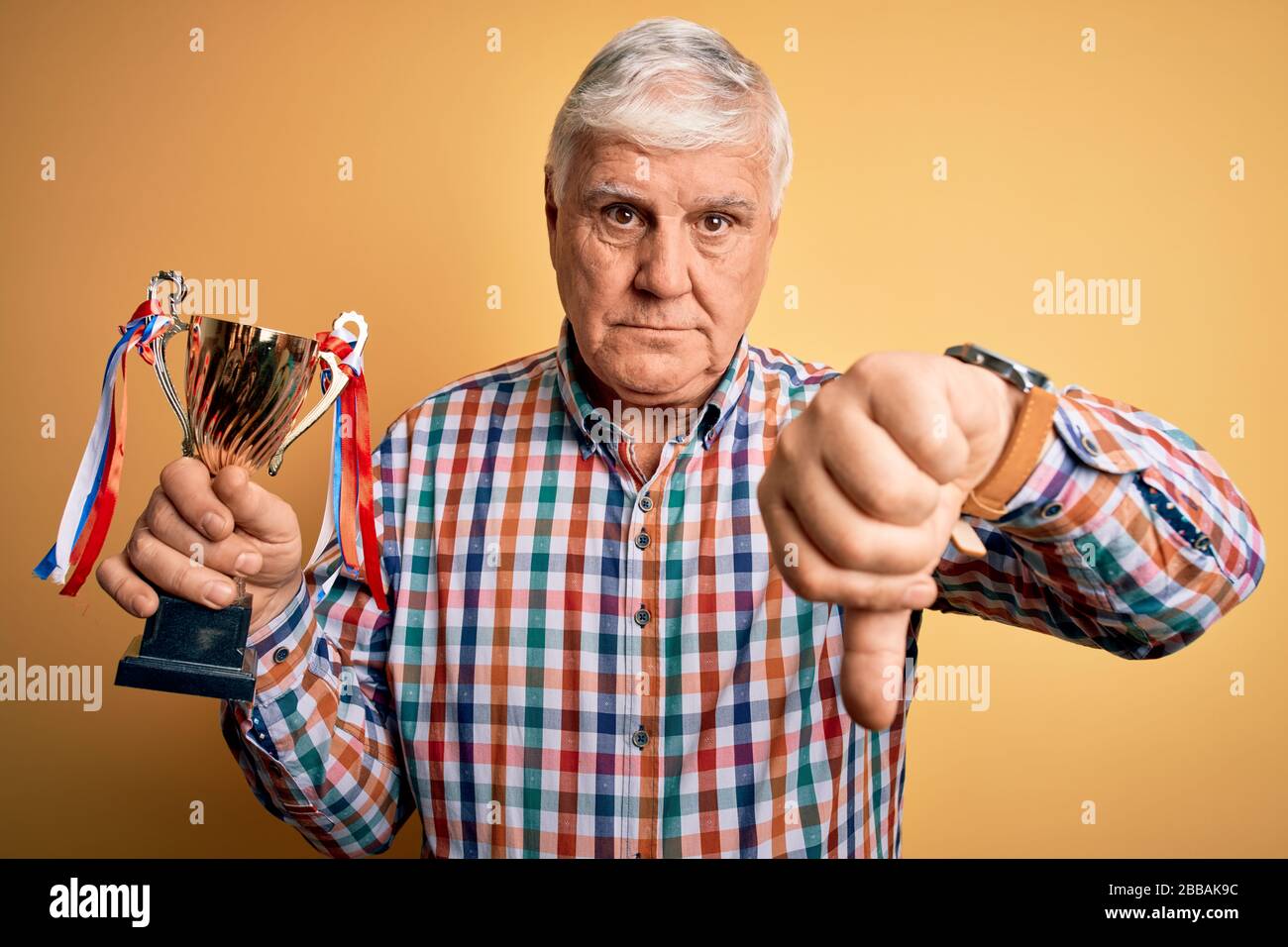 Senior handsome hoary champion man holding trophy award for victory ...