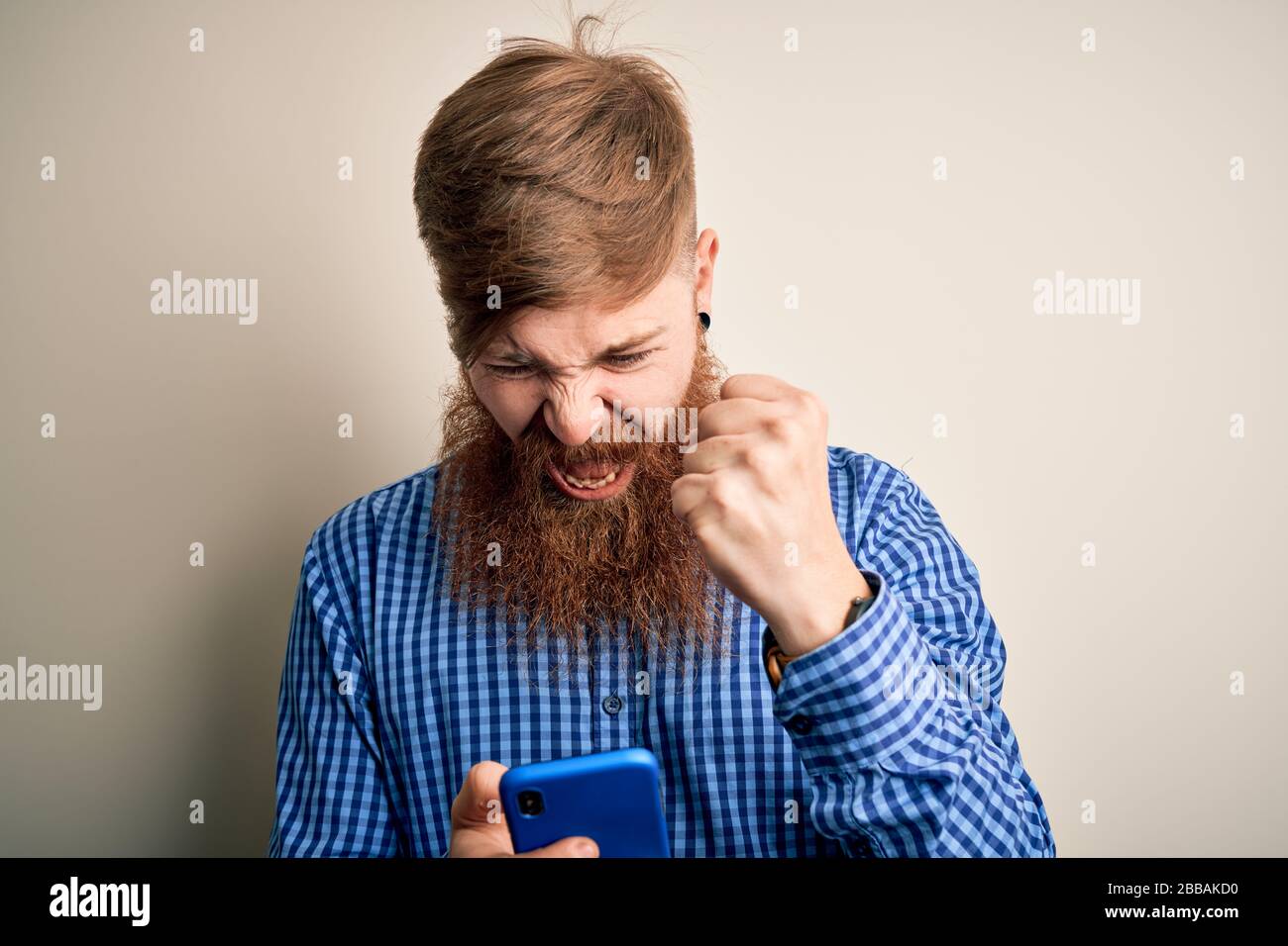 Redhead Irish man with beard using smartphone looking at screen over ...