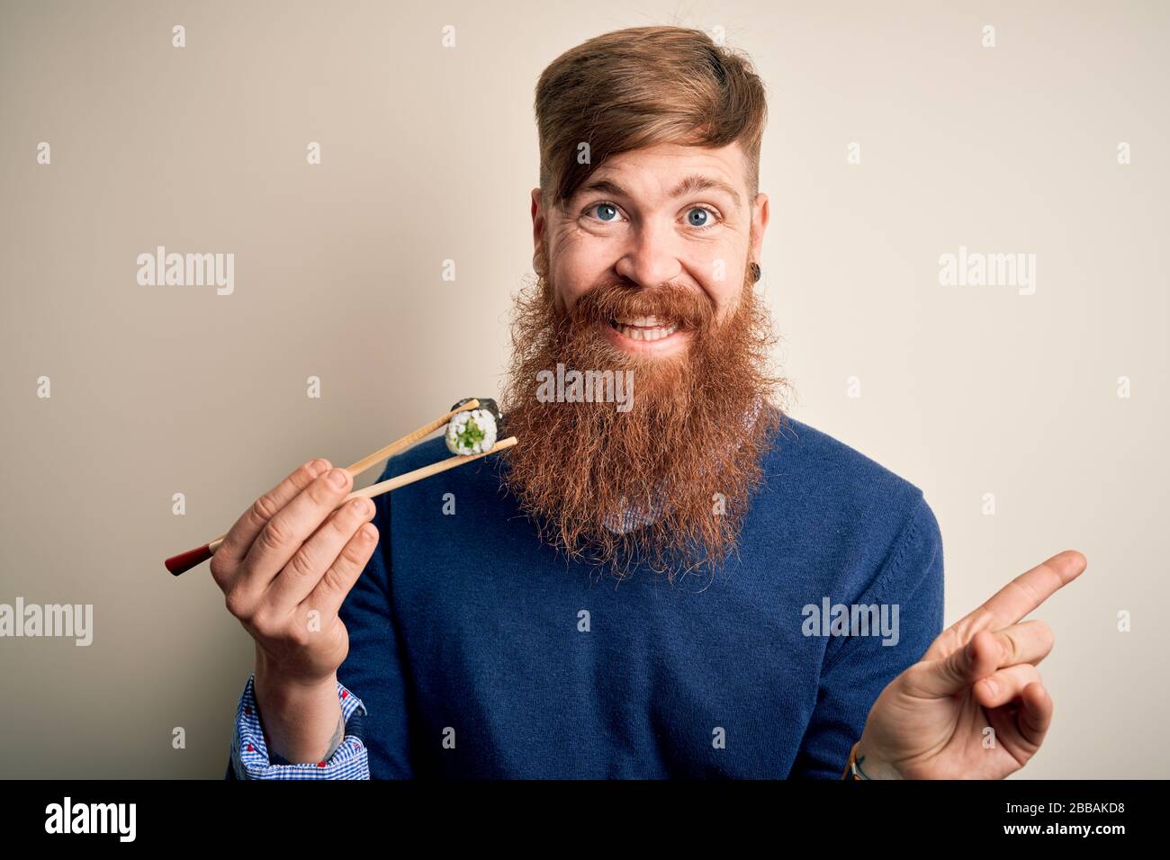 Redhead Irish man with beard eating green maki sushi using chopsticks ...