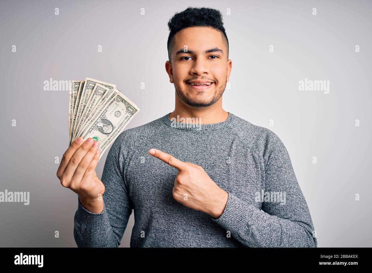 Young handsome man holding bunch of dollars banknotes over isolated ...