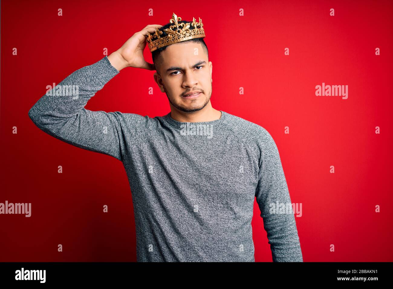 Young handsome man wearing golden crown of prince over isolated red ...
