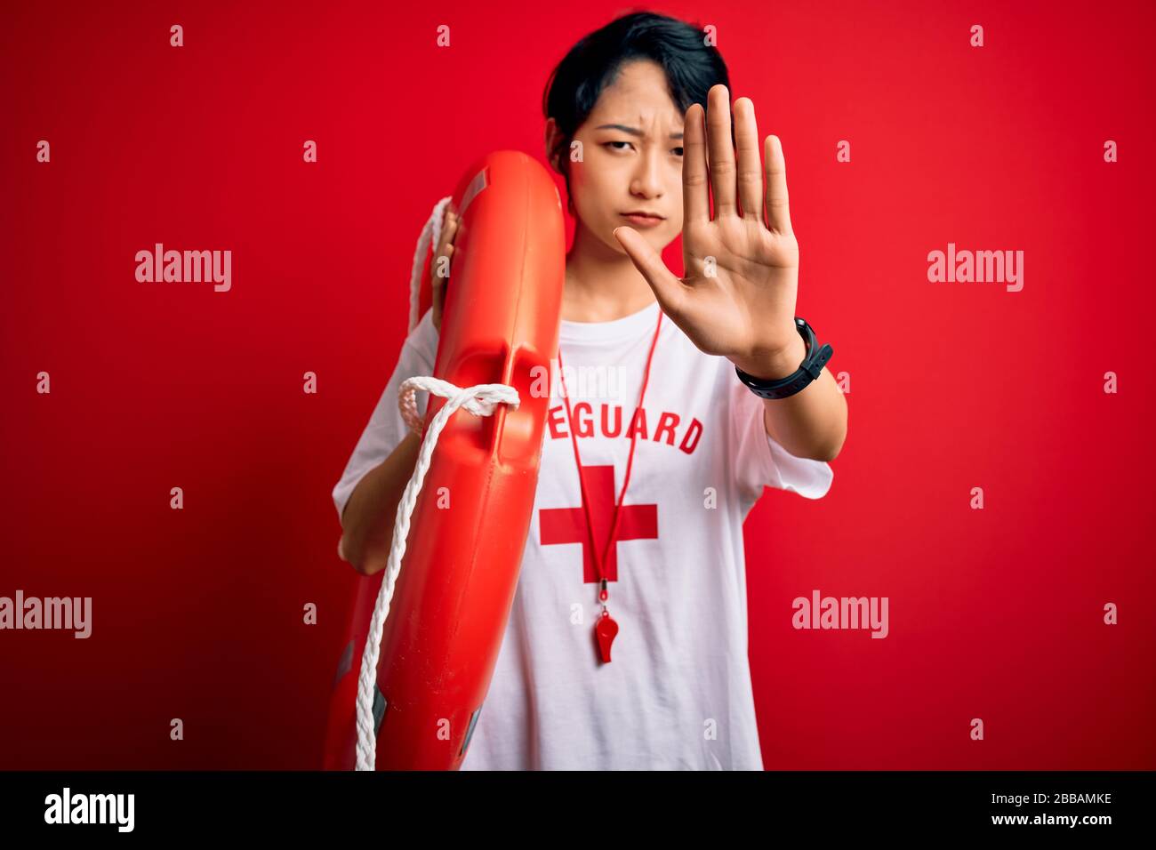 Young beautiful asian lifeguard girl using whistle holding orange float ...