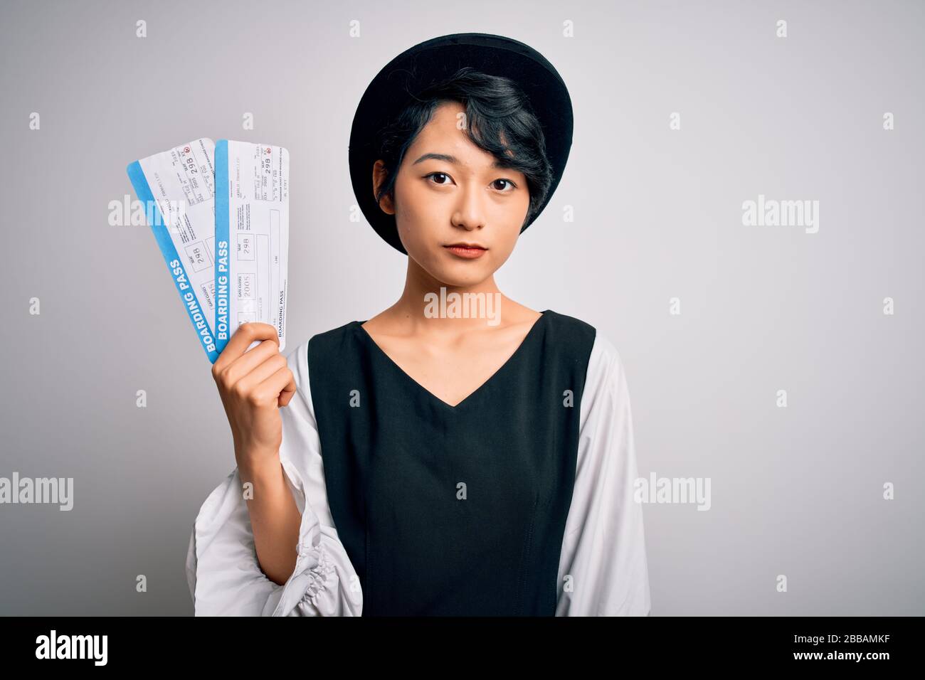 Young beautiful chinese tourist woman holding boarding pass airlane ...
