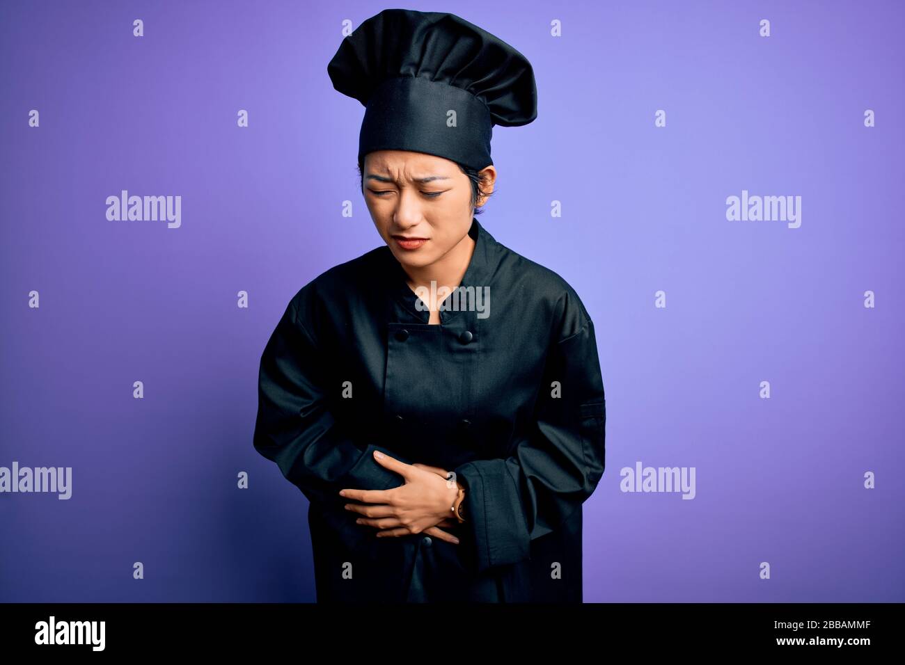 Young beautiful chinese chef woman wearing cooker uniform and hat over ...