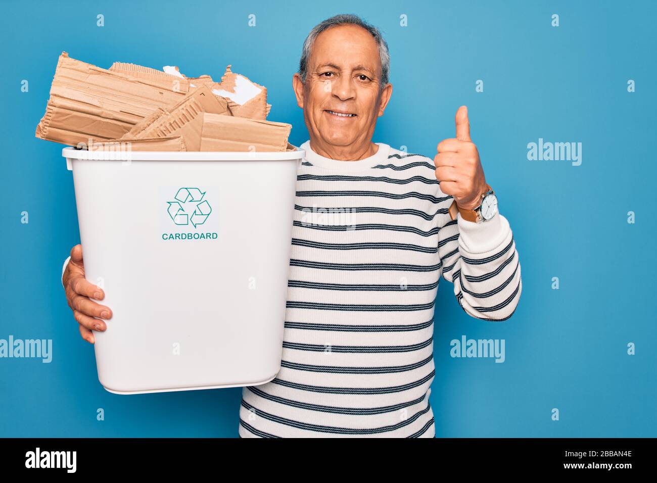 Senior man recycling holding trash can with cardboard to recycle over ...