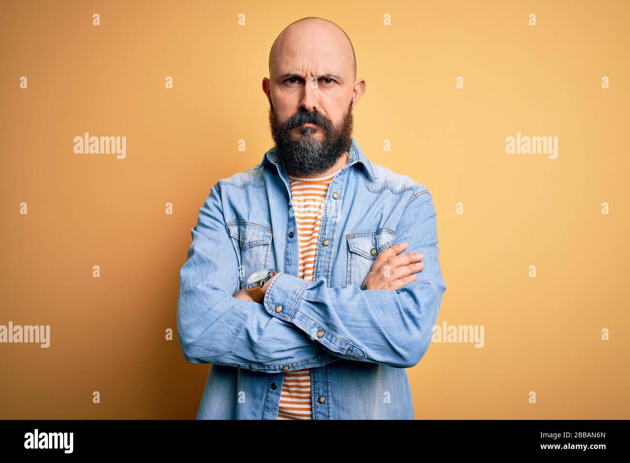 Handsome bald man with beard wearing casual denim jacket and striped t ...