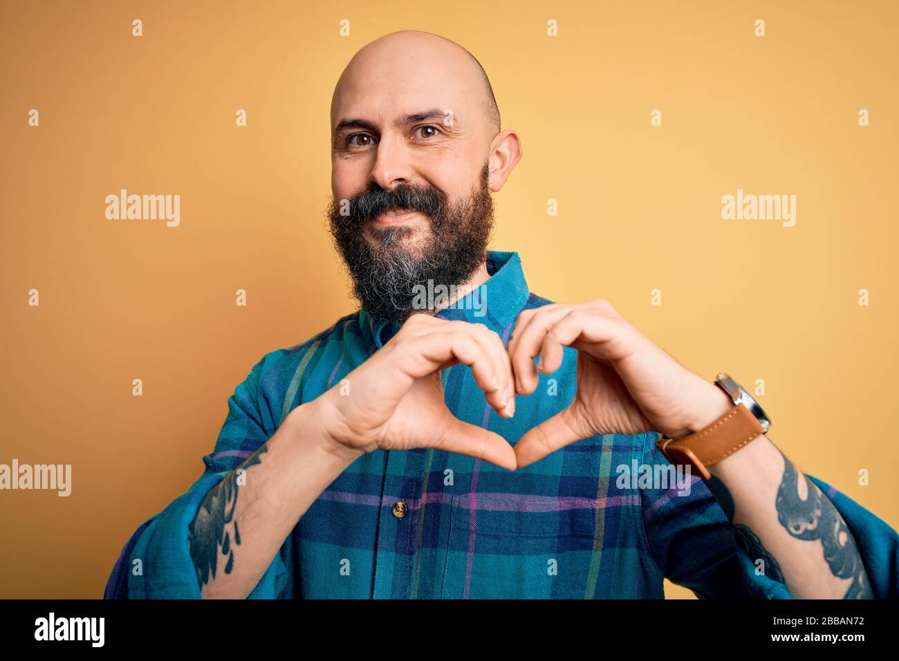 Handsome bald man with beard wearing casual shirt standing over ...