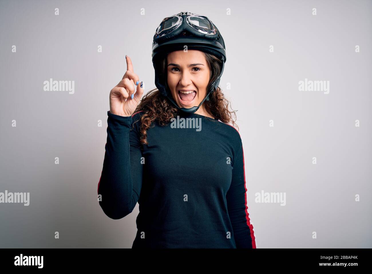 Beautiful motorcyclist woman with curly hair wearing moto helmet over ...