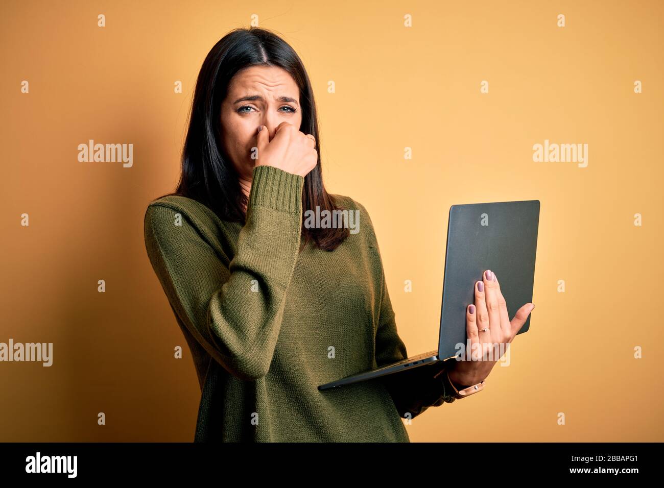 Young brunette woman with blue eyes working using computer laptop over ...