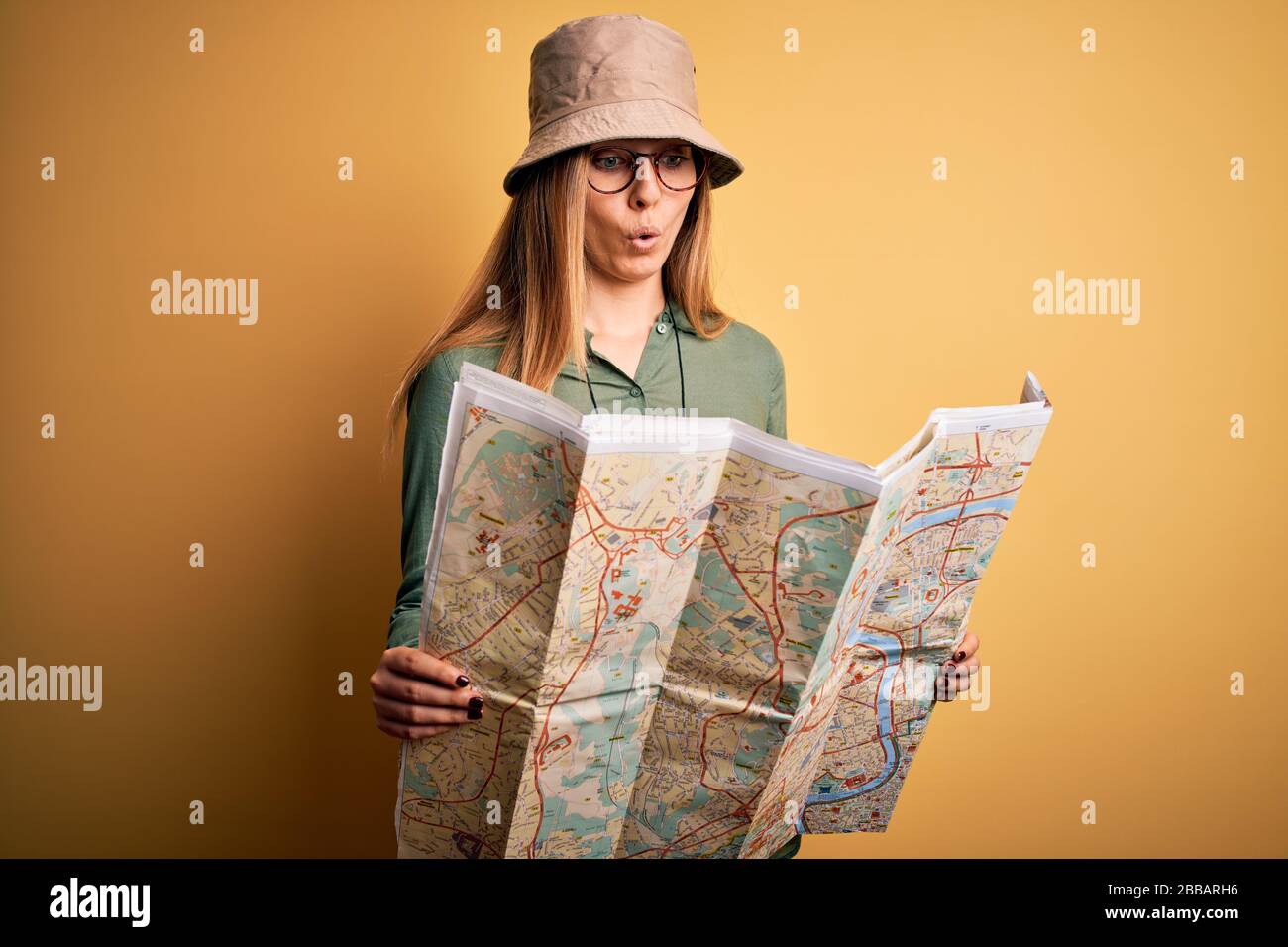 Blonde explorer woman with blue eyes on vacation wearing hat and ...