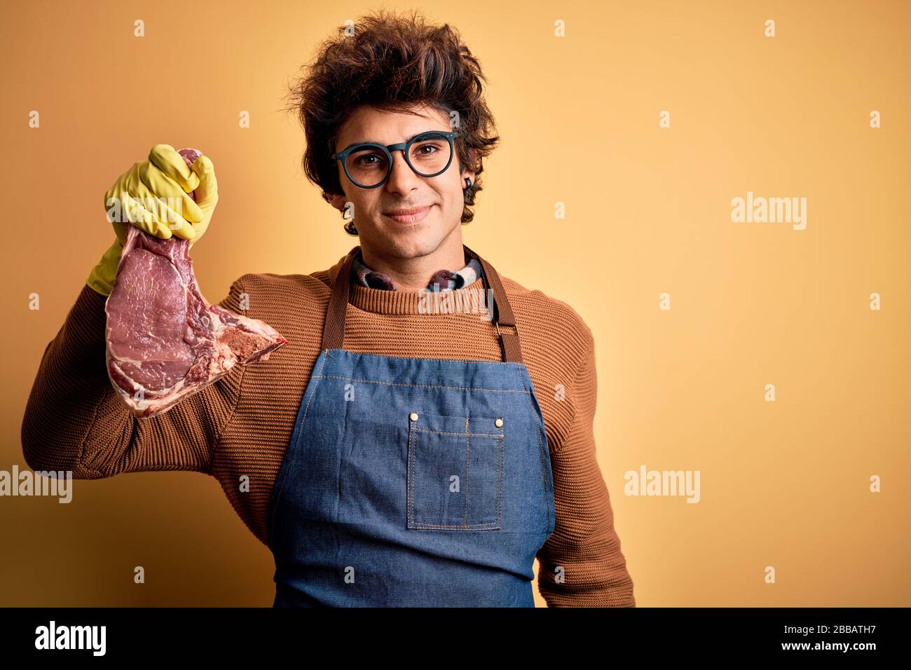 Young handsome butcher man holding meet steak standing over isolated ...