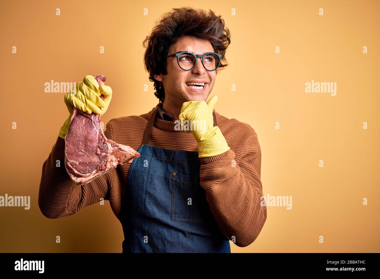 Young handsome butcher man holding meet steak standing over isolated ...