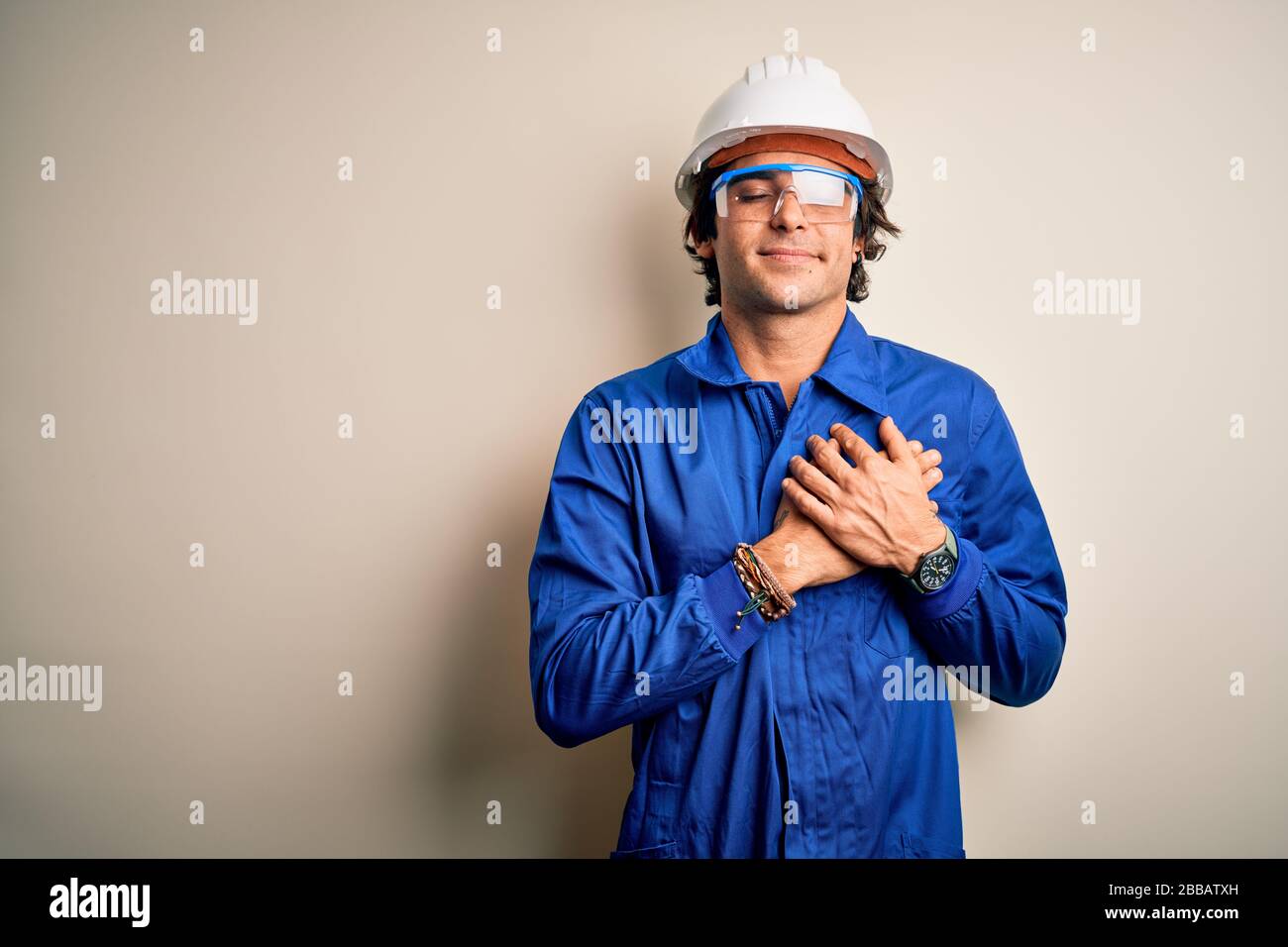 Young constructor man wearing uniform and security helmet over isolated ...