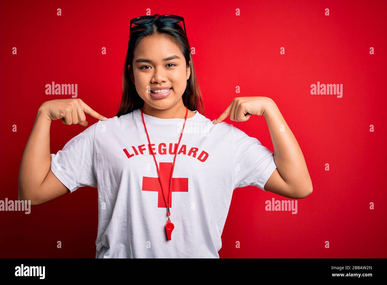 Young asian lifeguard girl wearing t-shirt with red cross using whistle ...
