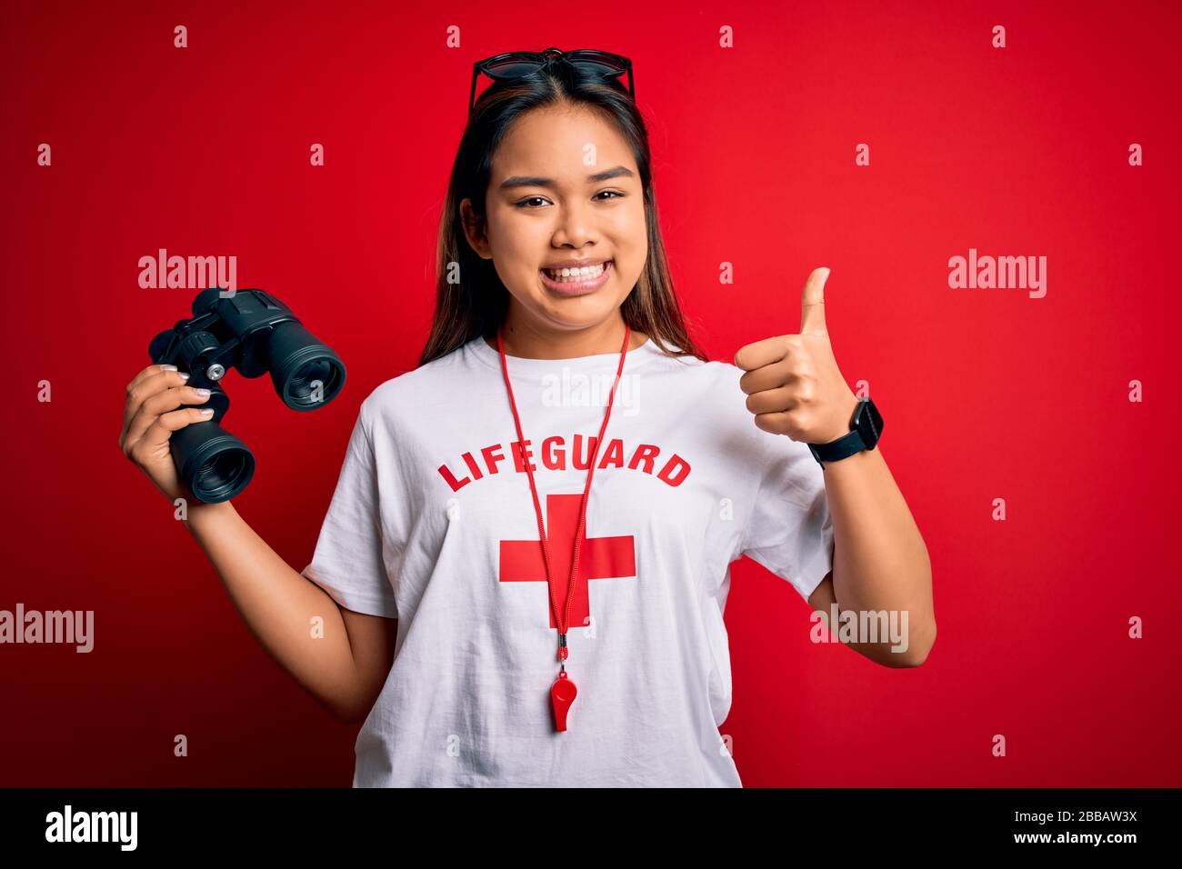 Young asian lifeguard girl wearing t-shirt with red cross using whistle ...
