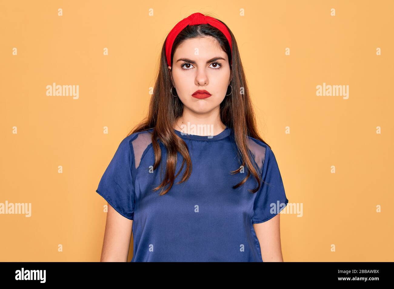 Young beautiful brunette woman wearing red lips over yellow background ...