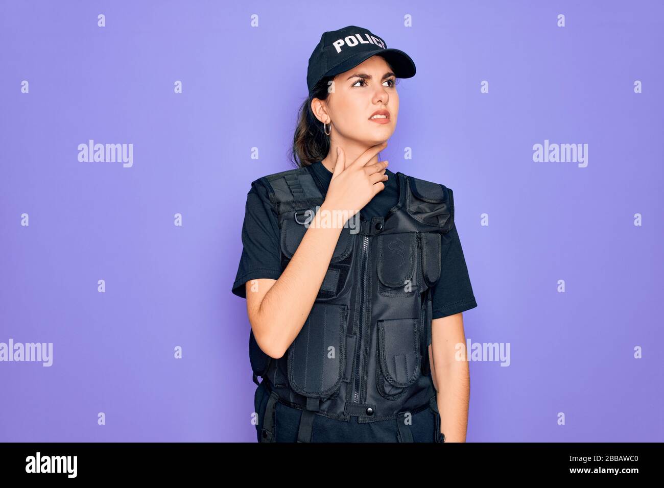 Young police woman wearing security bulletproof vest uniform over purple background Touching ...