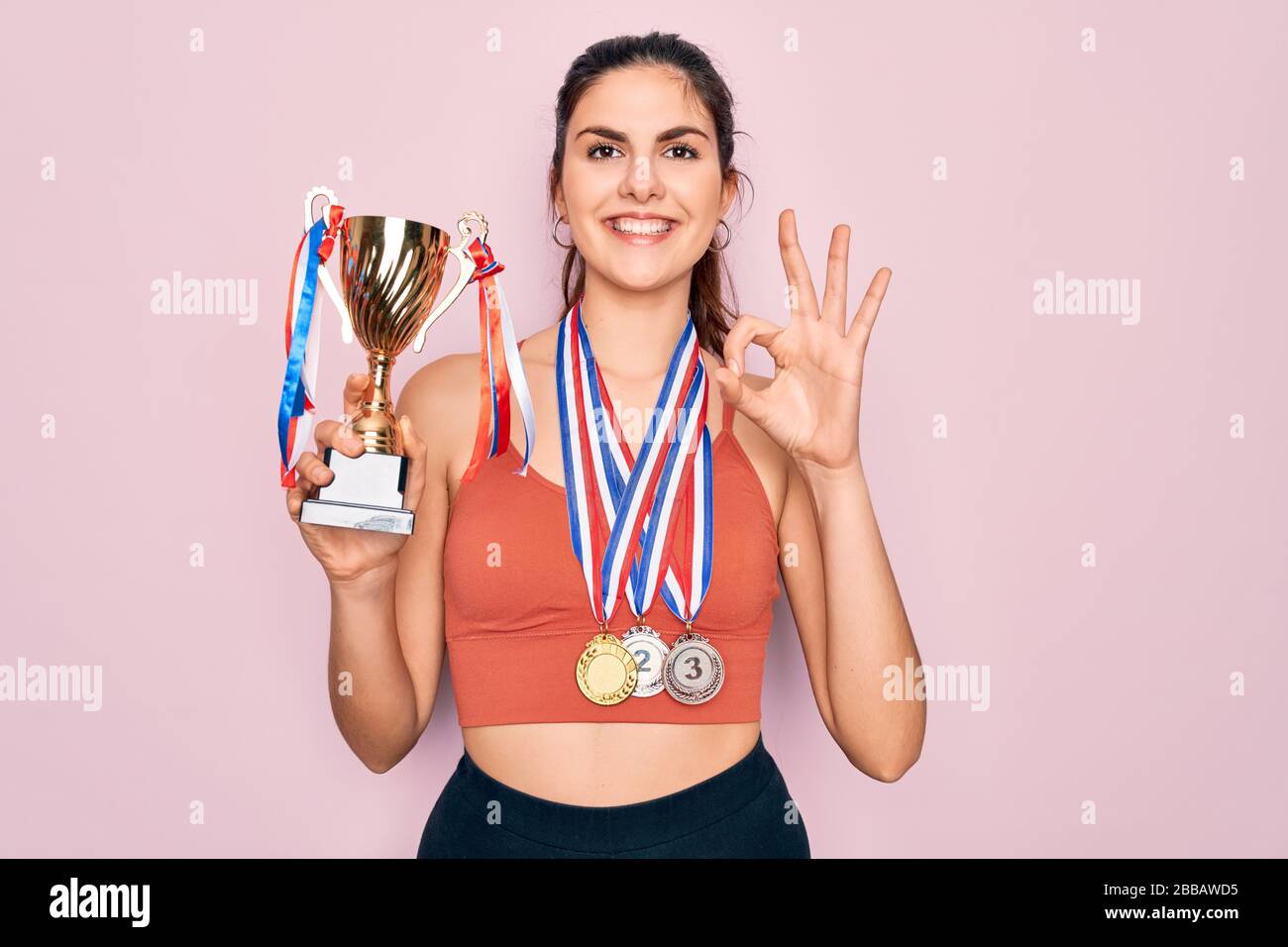 Young beautiful fitness winner athlete woman wearing sport medals and ...