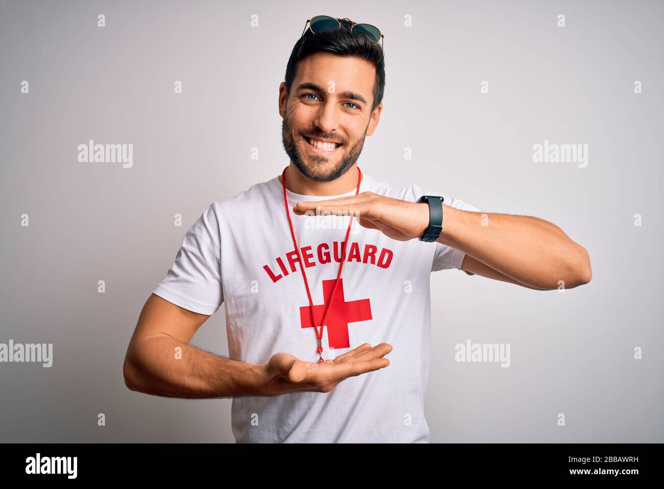 Young handsome lifeguard man with beard wearing t-shirt with red cross ...
