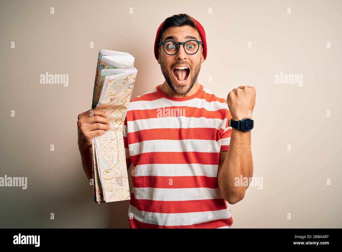 Young handsome tourist man on vacation wearing glasses holding city map ...