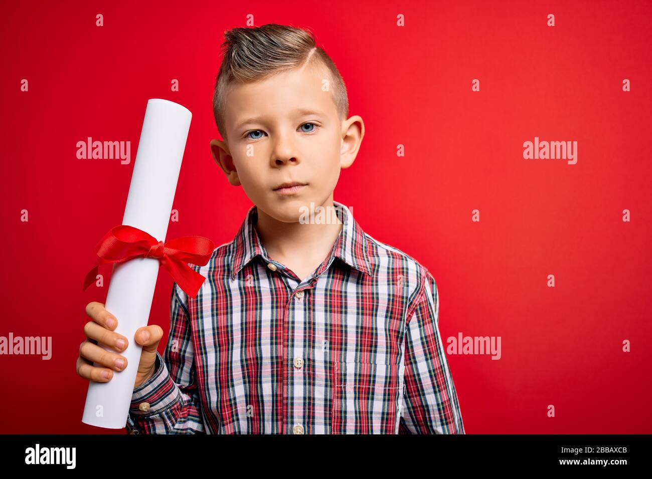 Young little caucasian student kid holding school degree over red ...