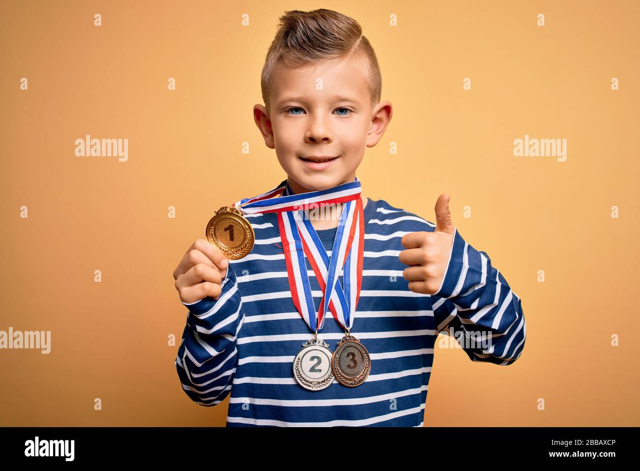 Young little caucasian winner kid wearing award competition medals over ...