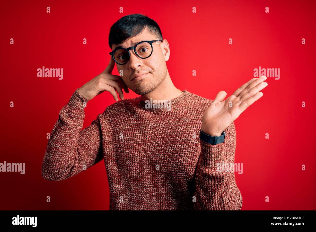Young handsome hispanic man wearing nerd glasses over red background ...