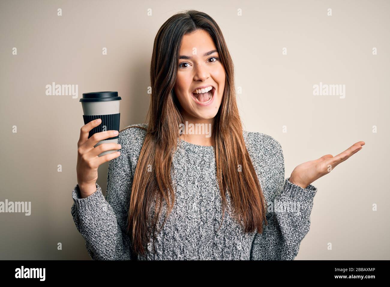 Young beautiful girl drinking cup of coffee standing over isolated ...