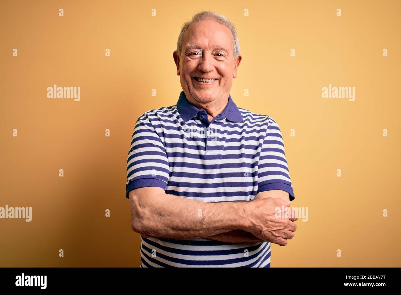Grey haired senior man wearing casual navy striped t-shirt standing ...
