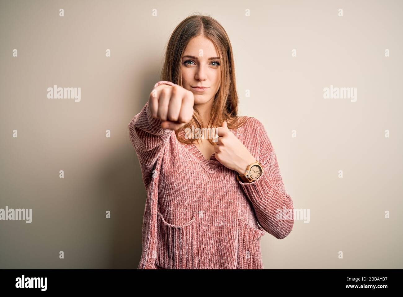 Young beautiful redhead woman wearing pink casual sweater over isolated ...