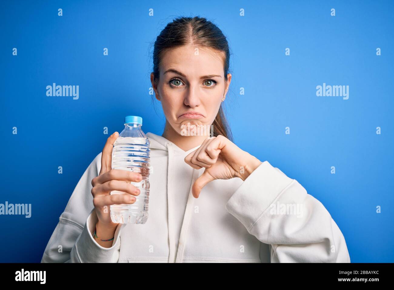 Young beautiful redhead woman doing sport drinking bottle of water over ...
