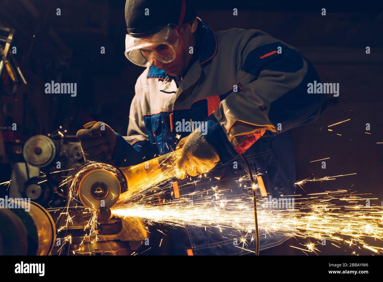 Locksmith in special clothes and goggles works in production. Metal ...