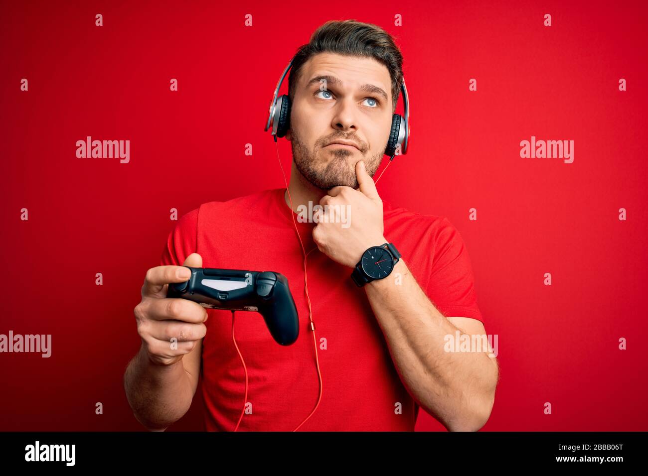 Young gamer man with blue eyes playing video games using gamepad ...