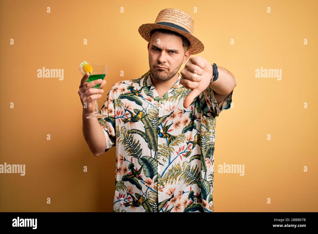 Young man on vacation wearing summer hat drinking a party cocktail over ...