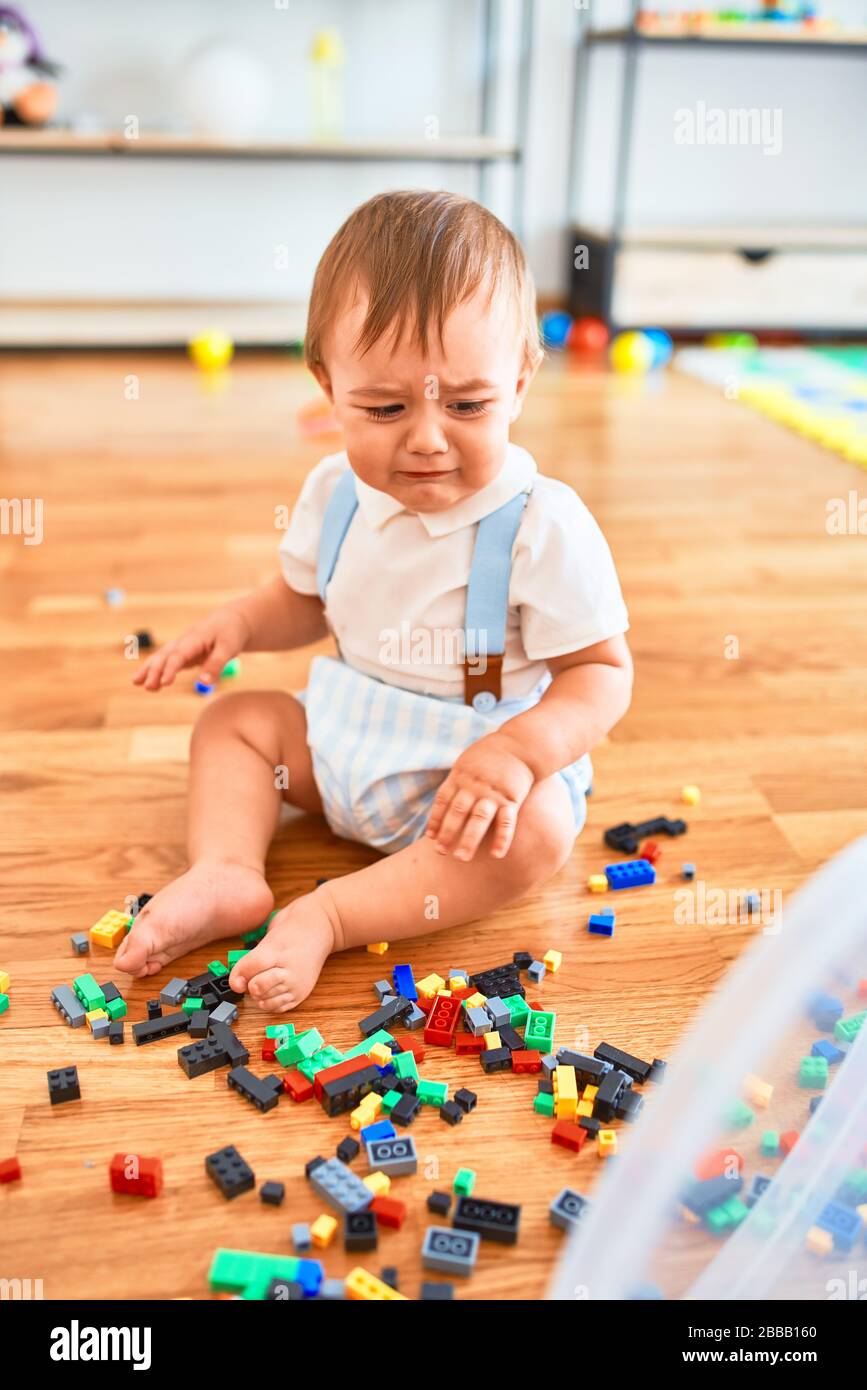 Adorable toddler crying around lots of toys at kindergarten Stock Photo ...