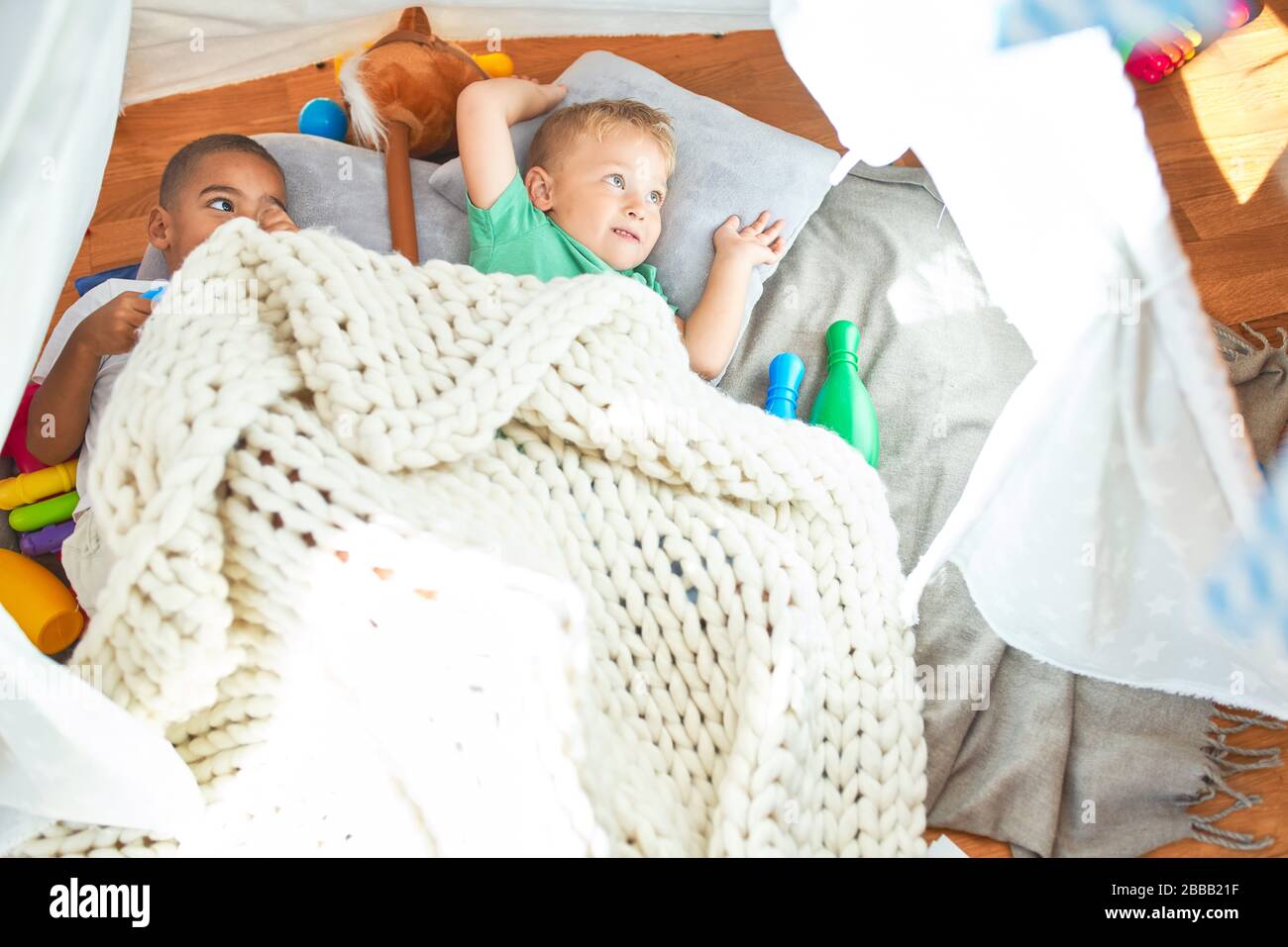 Adorable toddlers playing inside tipi around lots of toys at ...