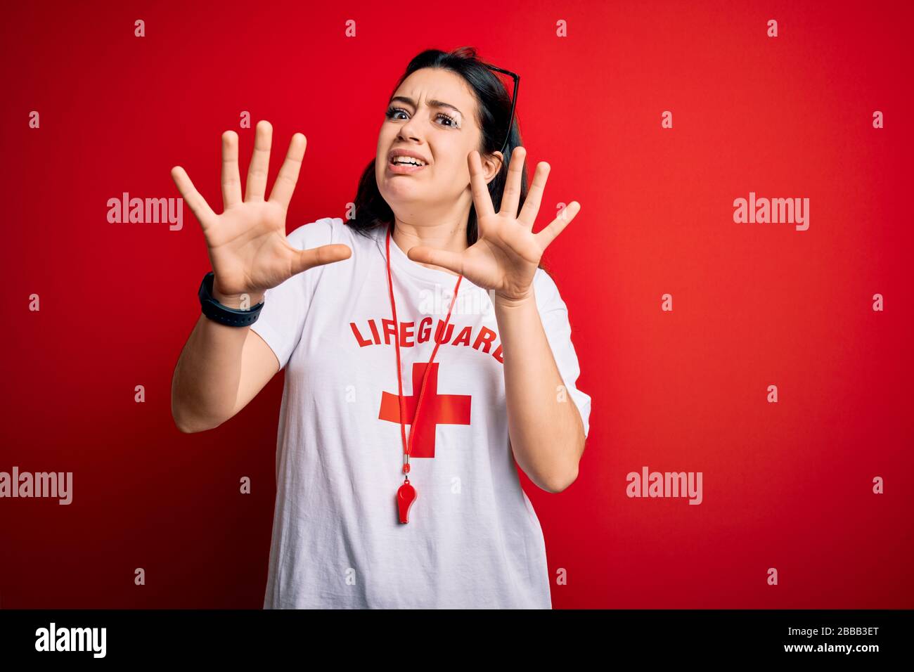 Young lifeguard woman wearing secury guard equipent over red background ...