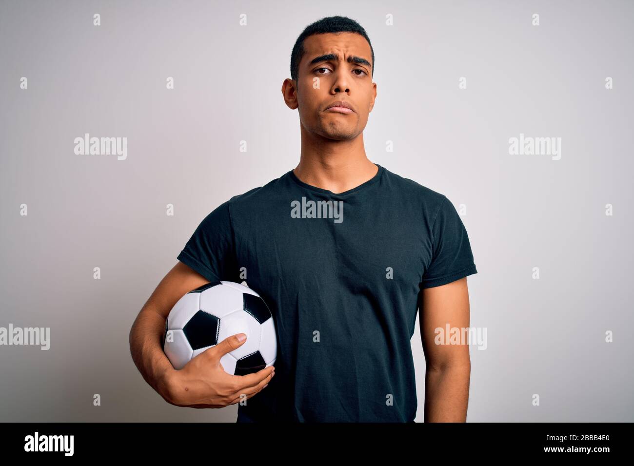Handsome african american man playing footbal holding soccer ball over ...