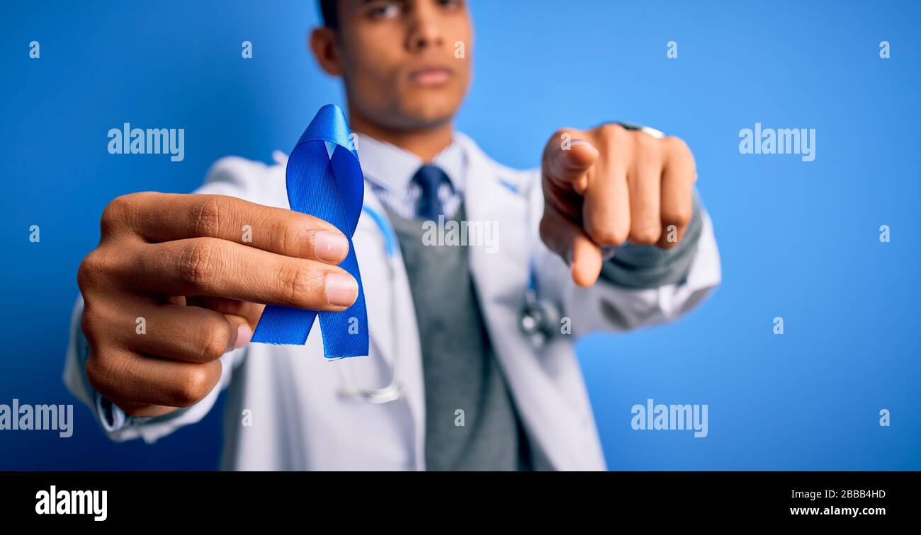 Young handsome african american doctor man holding blue cancer ribbon ...